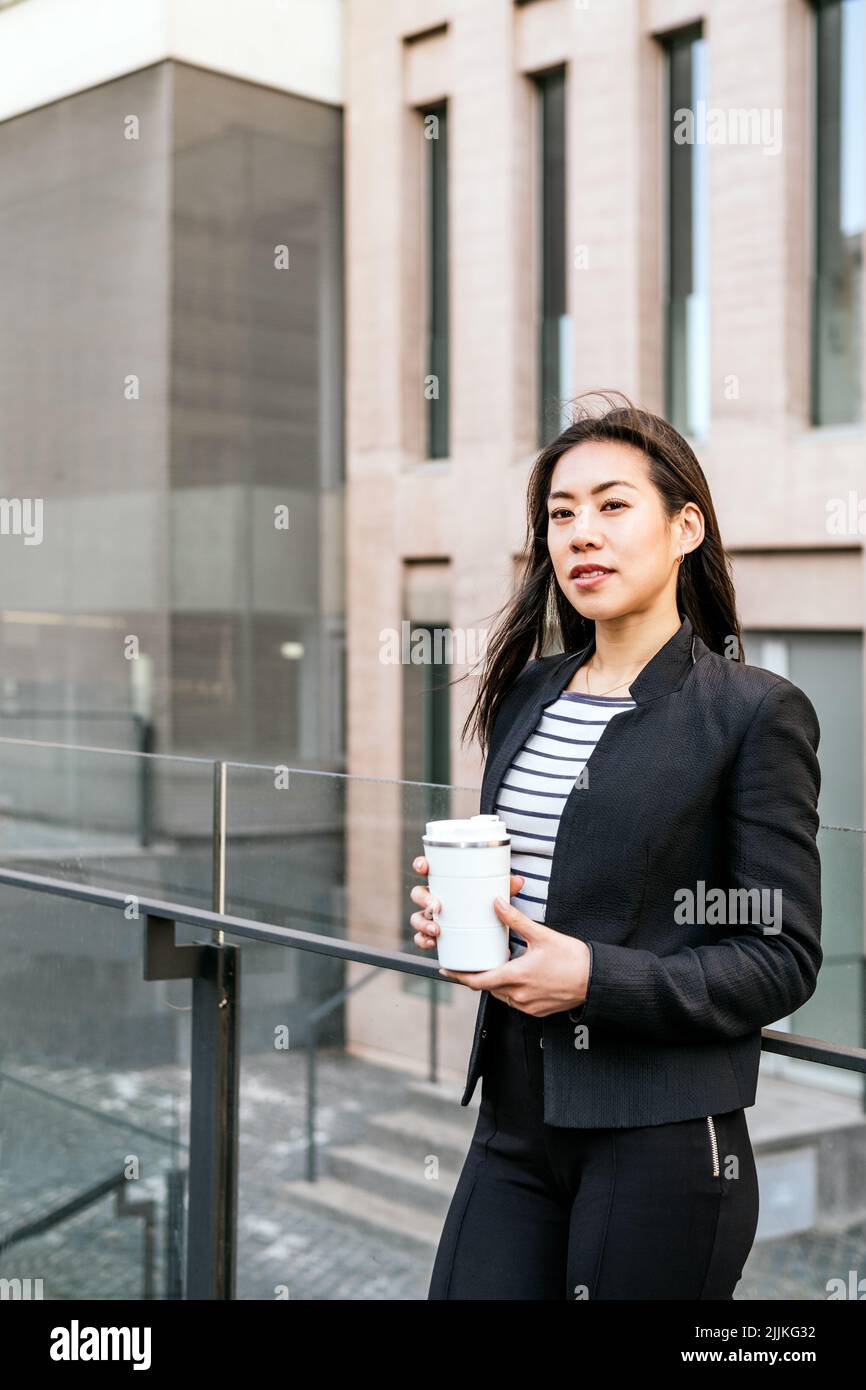 Confident young Asian female manager in formal clothes with reusable ...