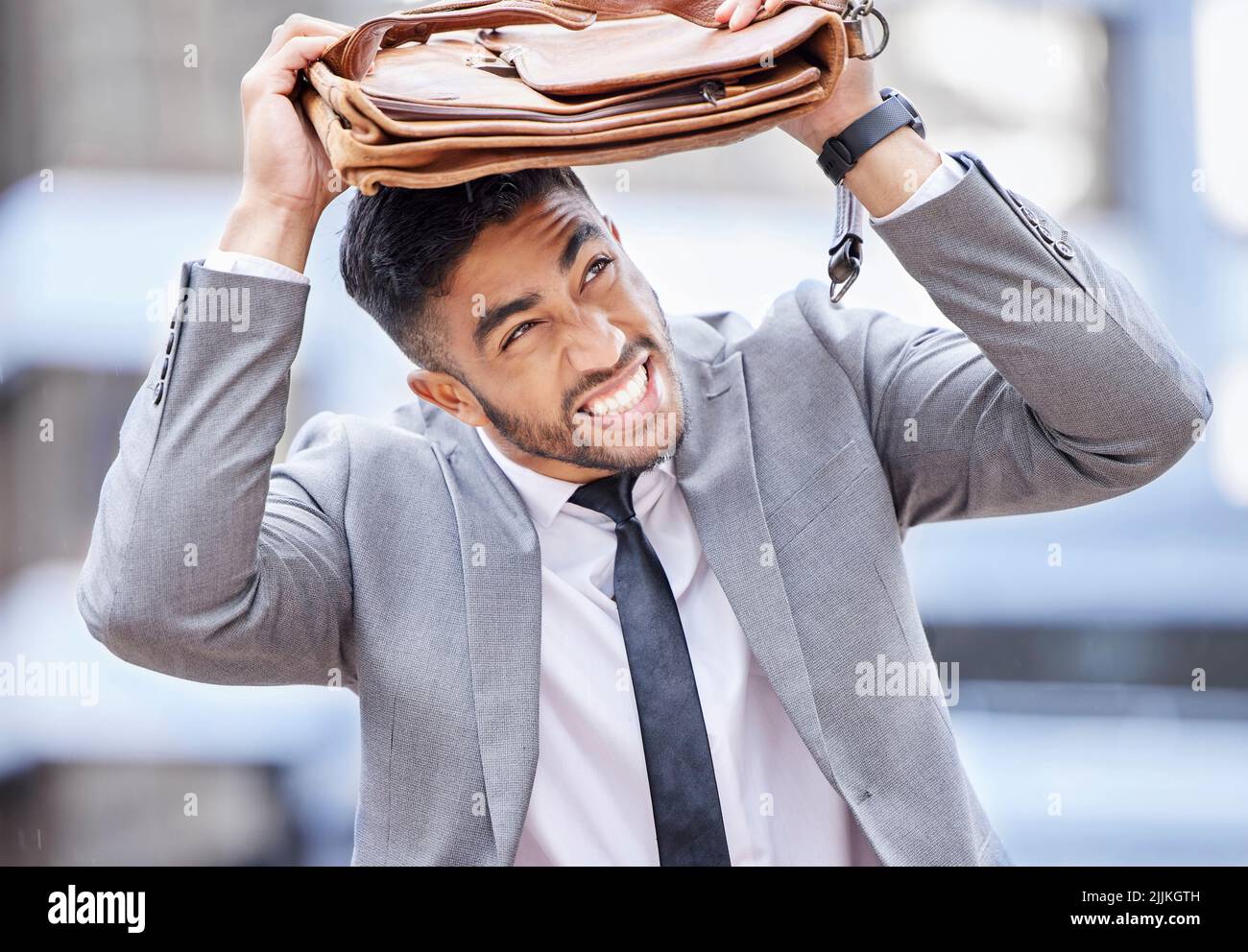 Hope I dont get drenched in this rain. a young businessman covering his ...