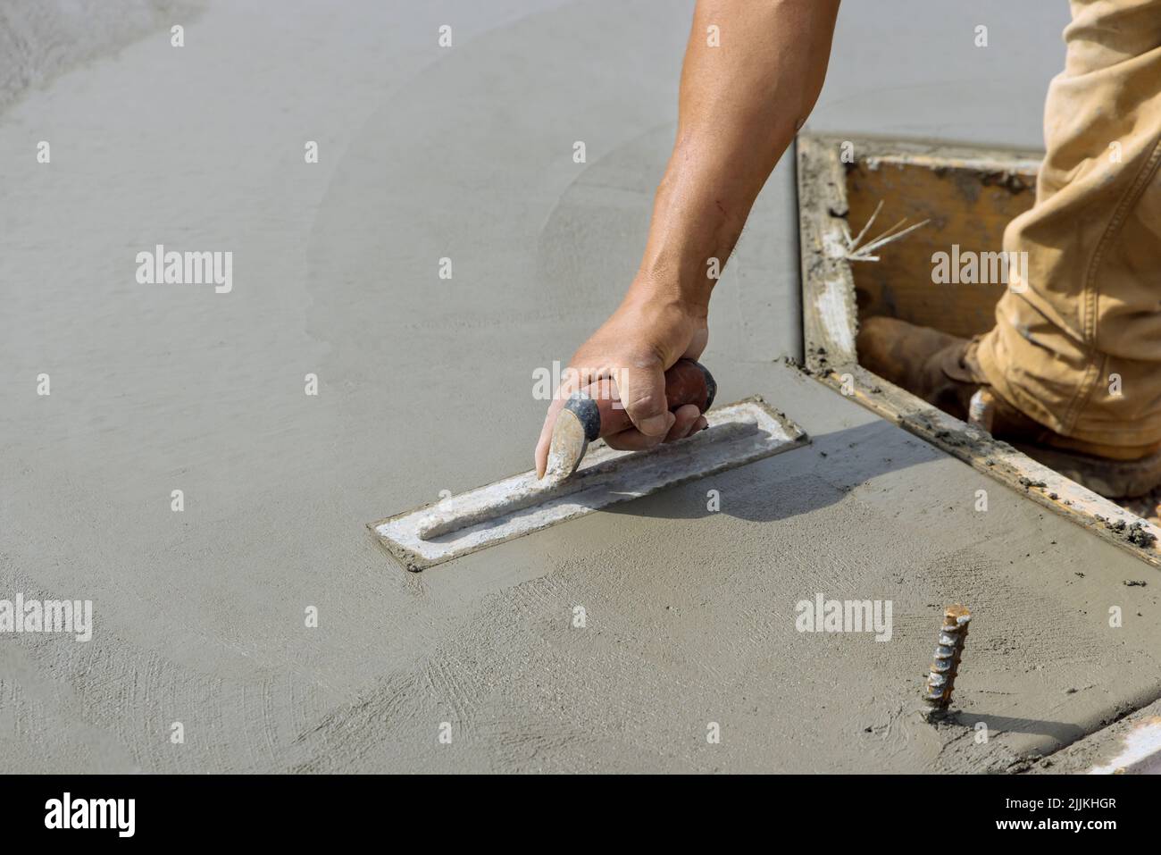 In this a mason worker is holding a steel trowel and smoothing ...