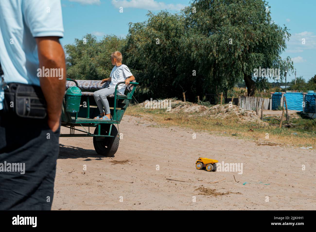 The beautiful shot of a boy in a carriage pulling his toy truck by a ...