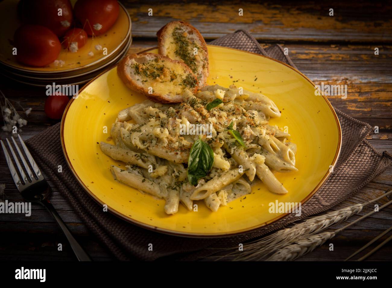 An angle shot of pasta penne served with bruschetta bread slices on a ...