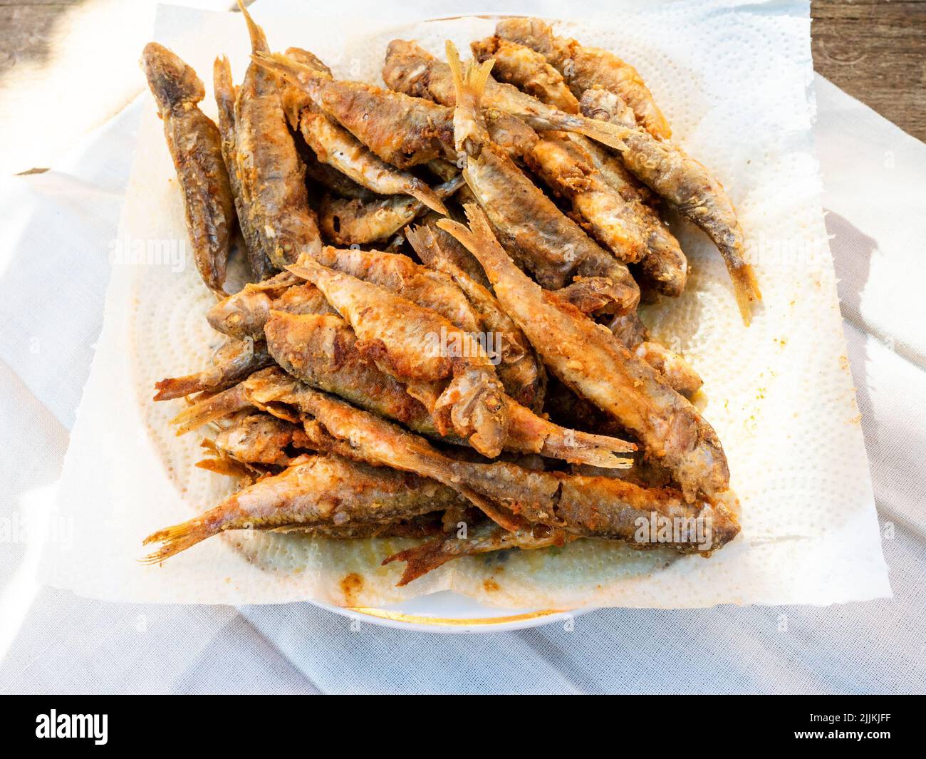 above view of fried small Black Sea surmullet fishes on white paper ...