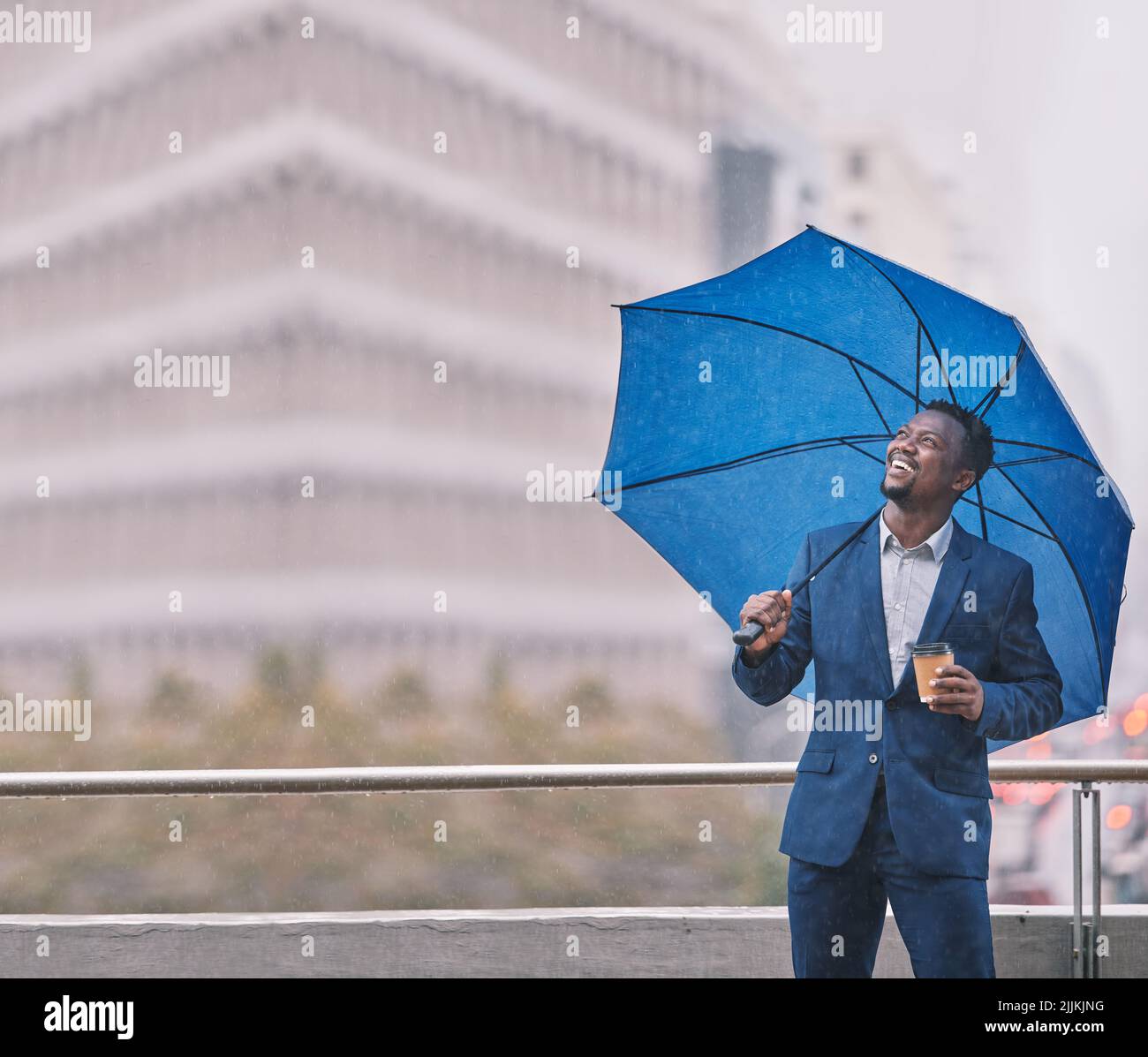 Its really pouring down. a young businessman holding an umbrella in the ...