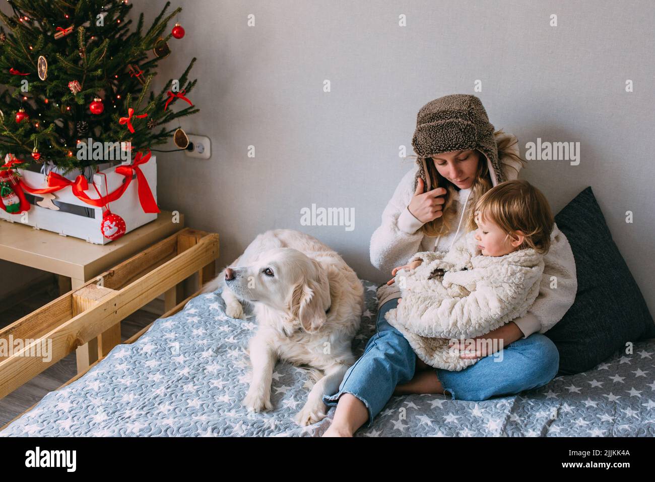 Mom and daughter comfortably cuddle at home with their pet Labrador ...
