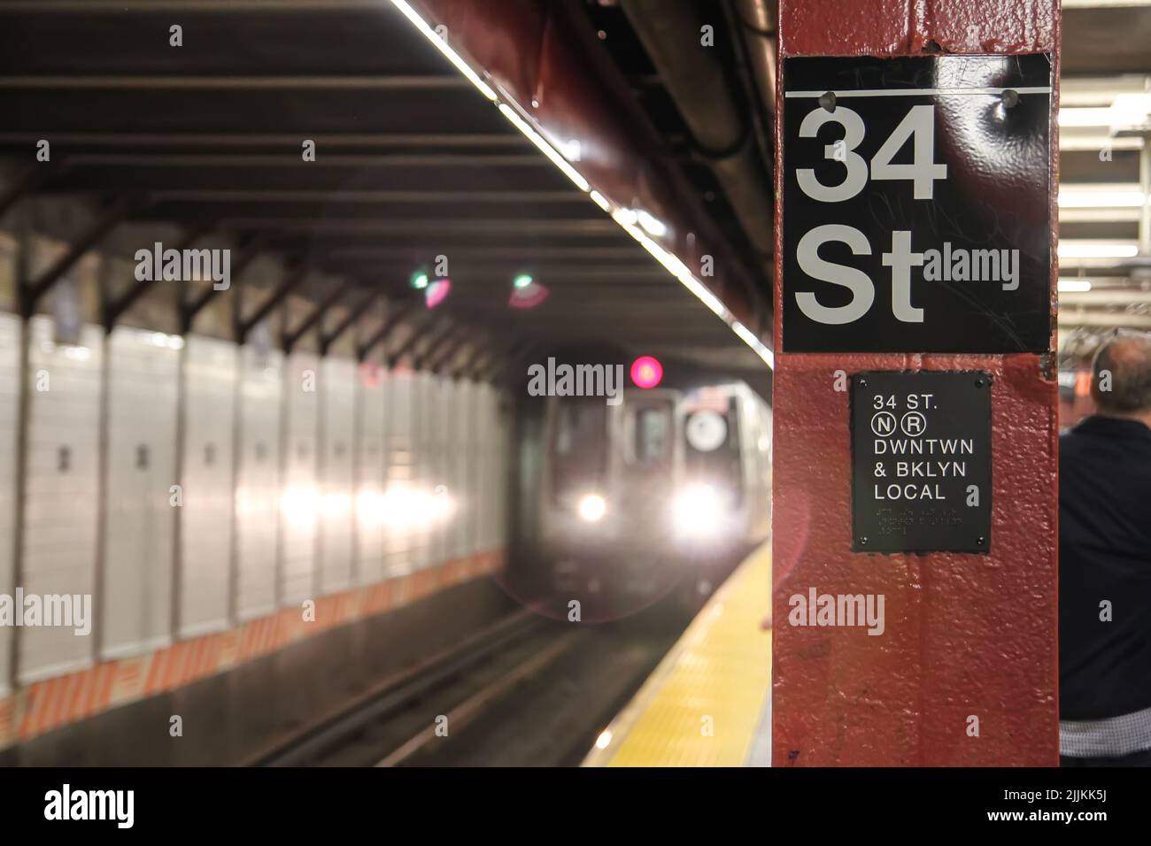 A shot of a column in the New York subway with a train approaching the ...