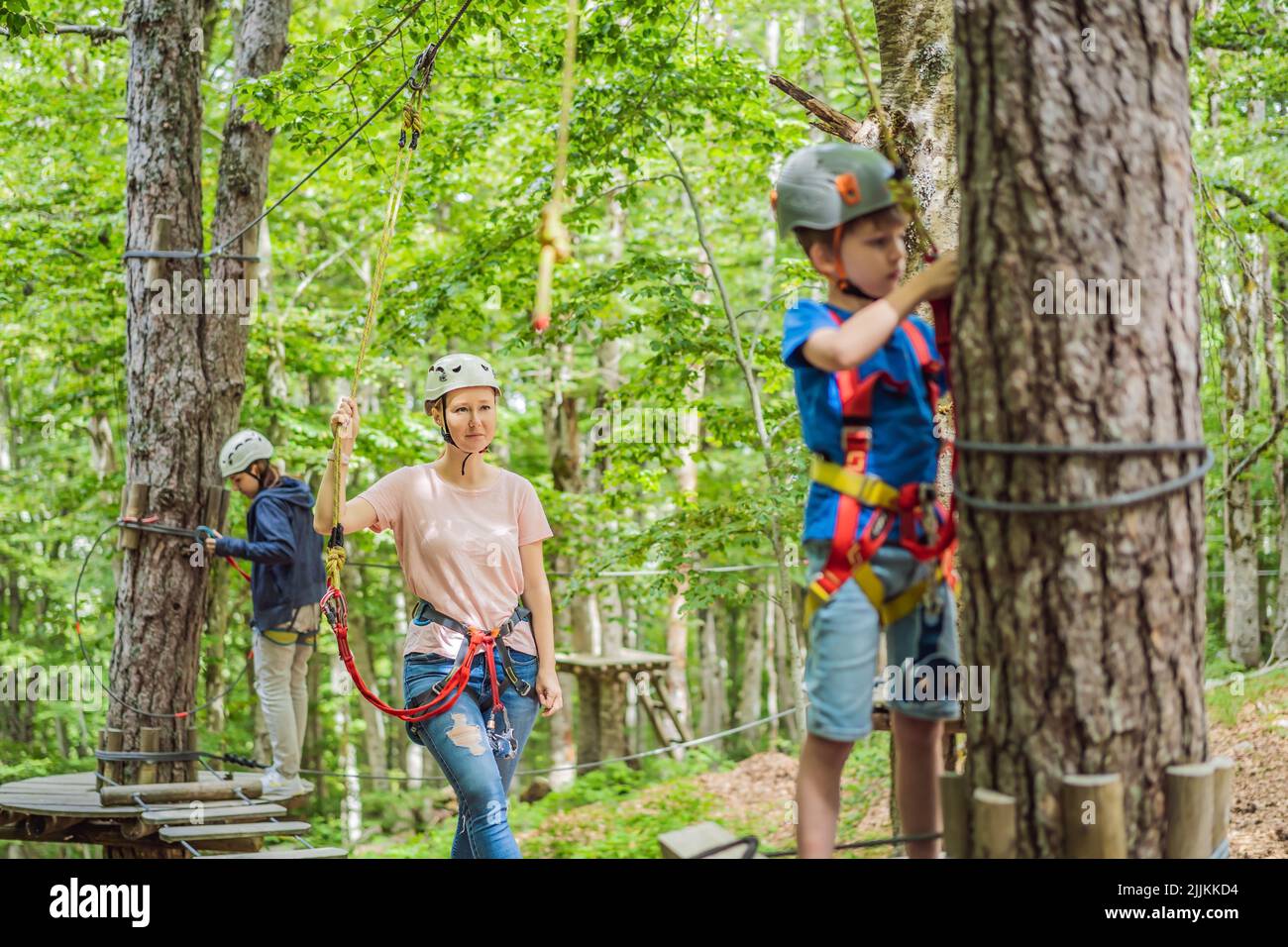Mother and son climbing in extreme road trolley zipline in forest on ...