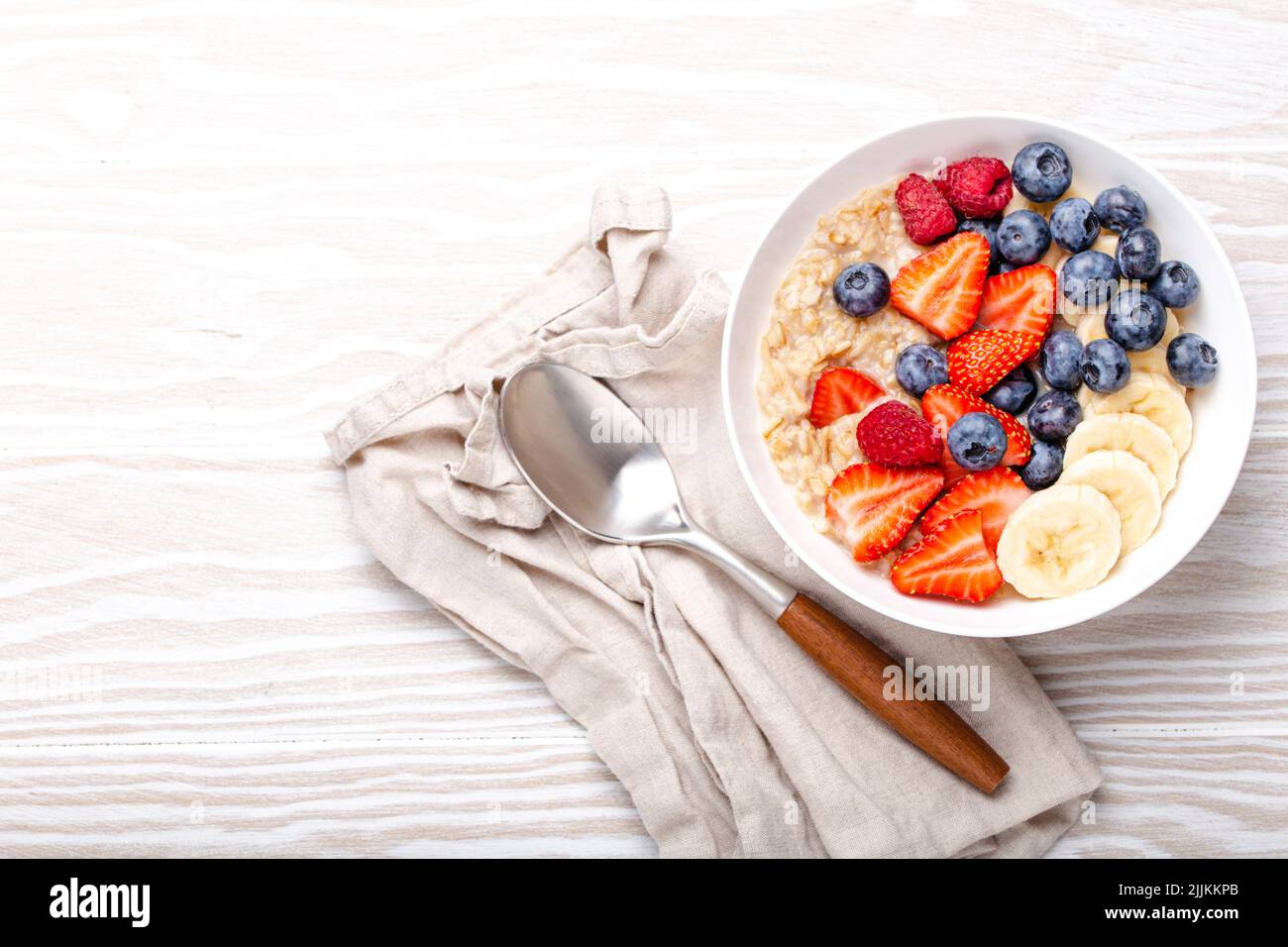 Oatmeal porridge with fruit and berries on white wooden table Stock ...
