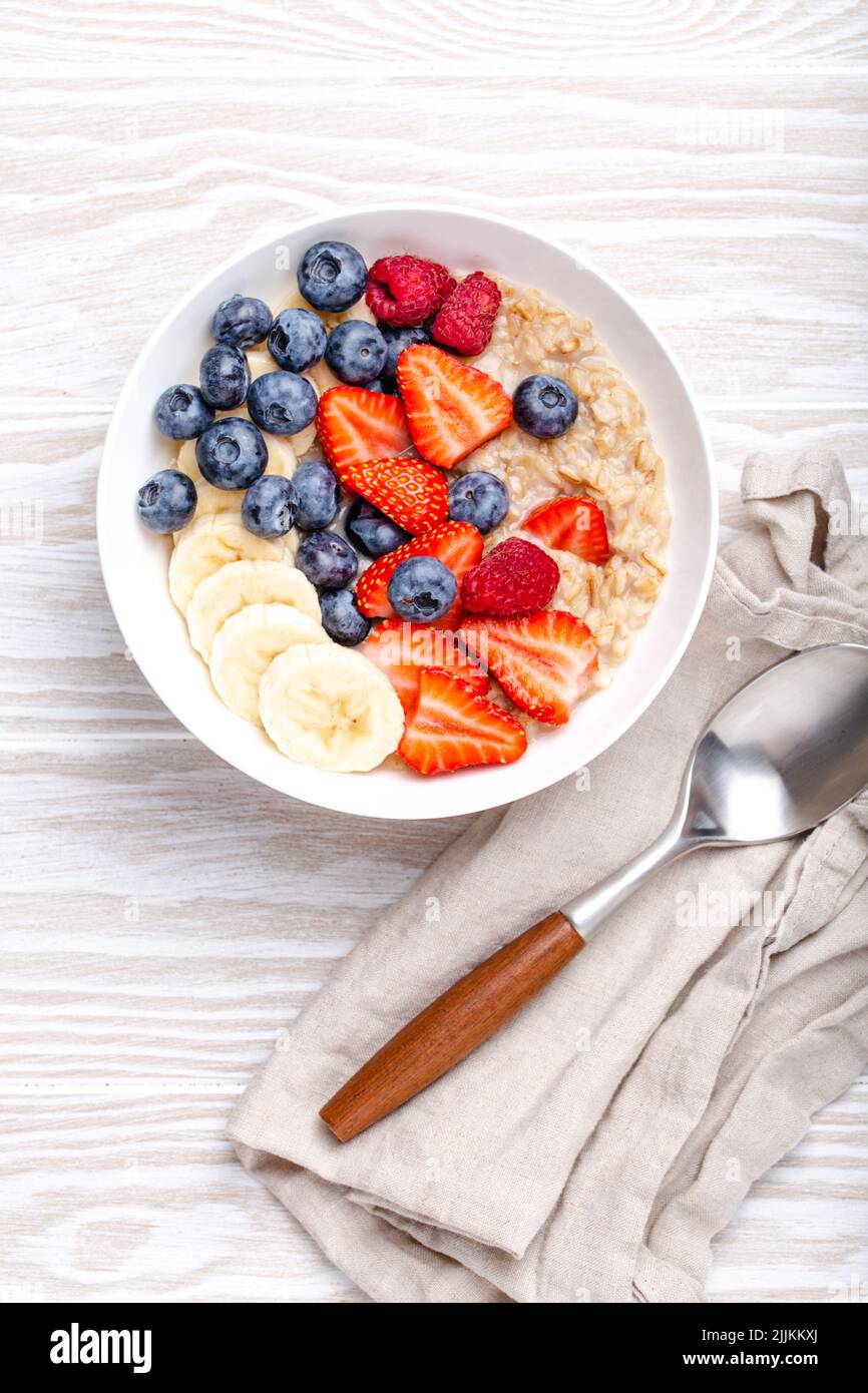 Oatmeal porridge with fruit and berries on white wooden table Stock ...