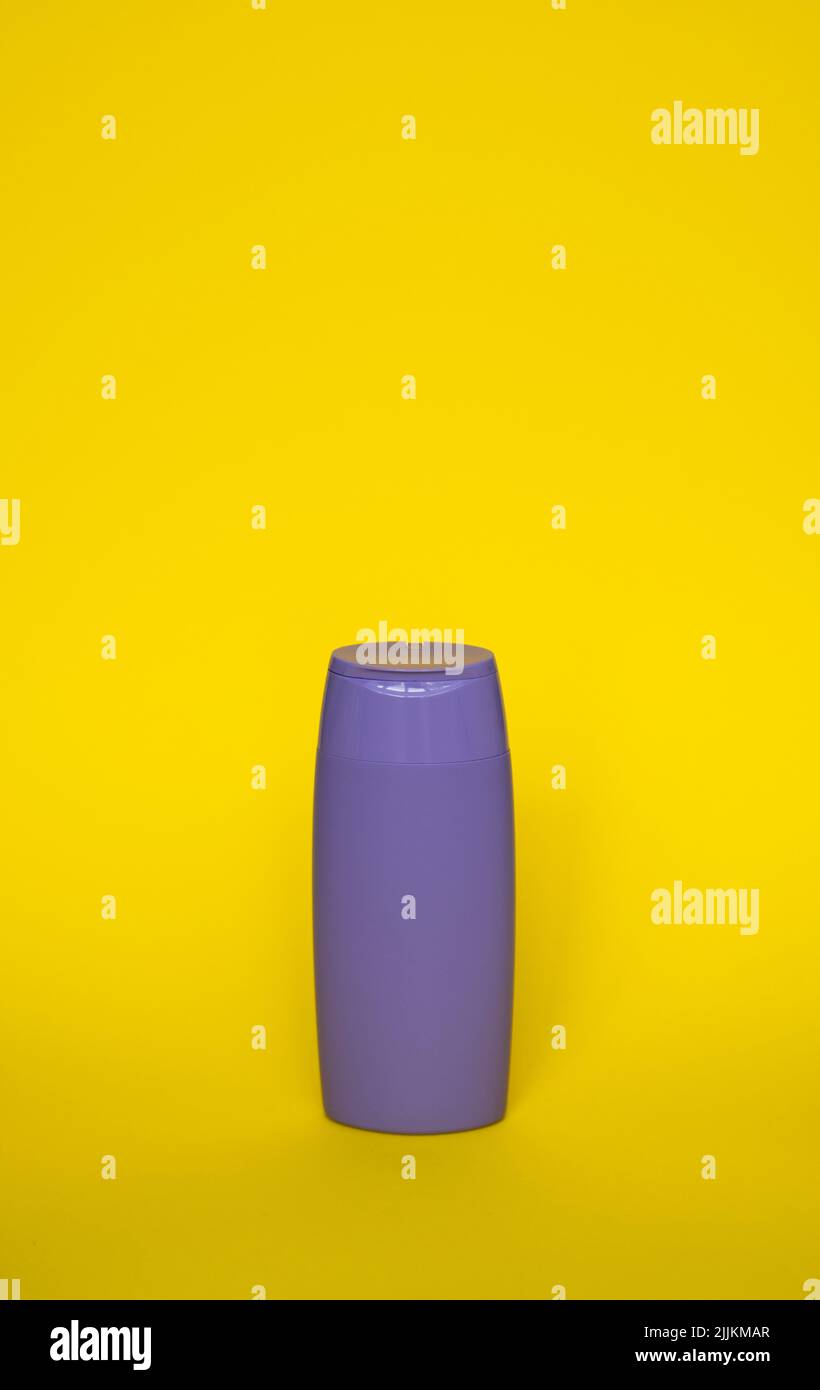 Violet plastic shampoo bottle isolated on yellow background. Skin care ...