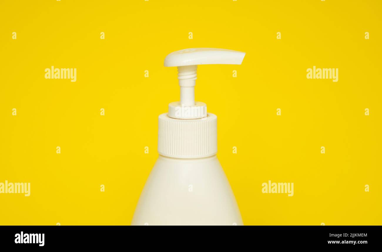 White plastic soap or shampoo dispenser pump bottle isolated on yellow ...