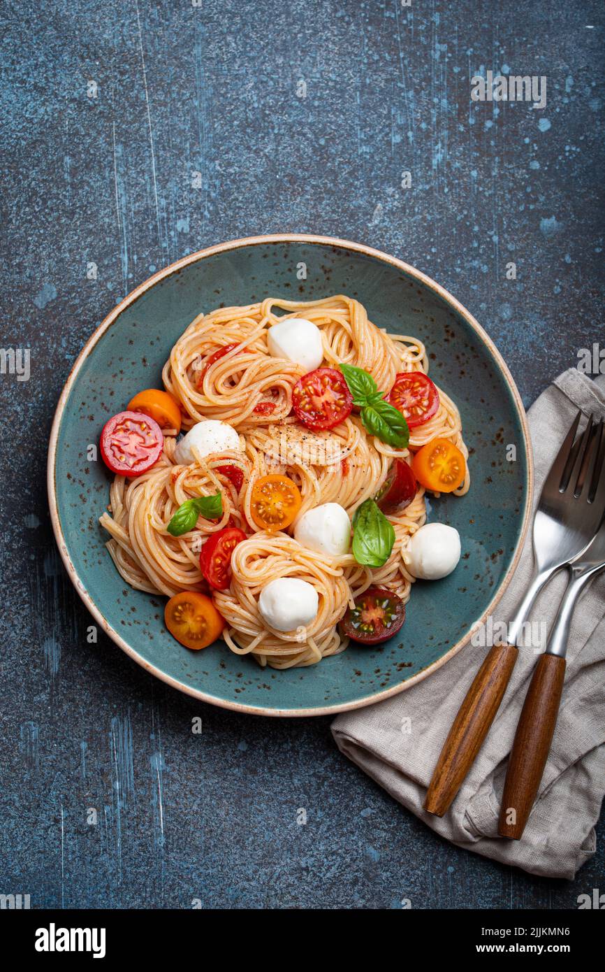 Spaghetti with mozzarella, colourful cherry tomatoes, fresh basil on ...