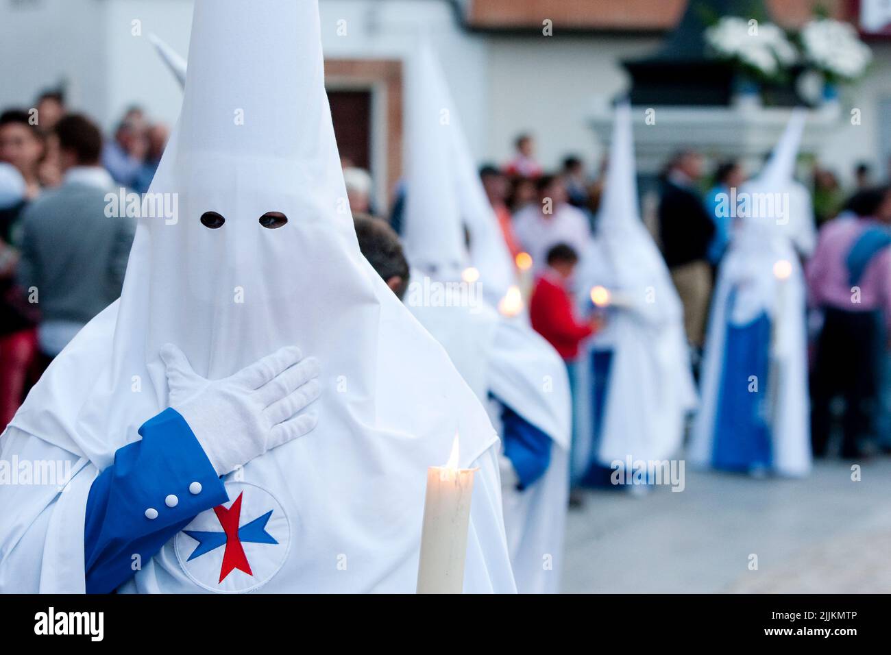 A person with a white, traditional capirote at the Spanish Holy Week ...