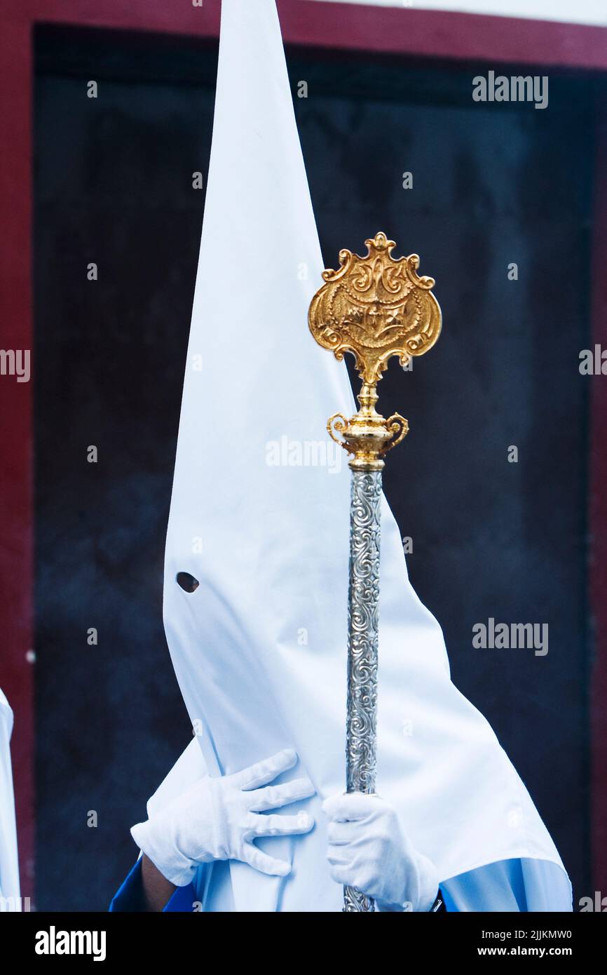 A vertical shot of a person with a white, traditional capirote at the ...