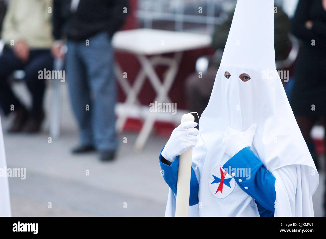 A vertical shot of a person with a white, traditional capirote at the ...