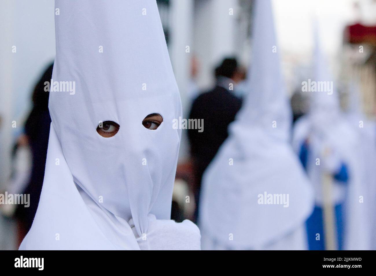 A portrait of a person with a white, traditional capirote at the ...