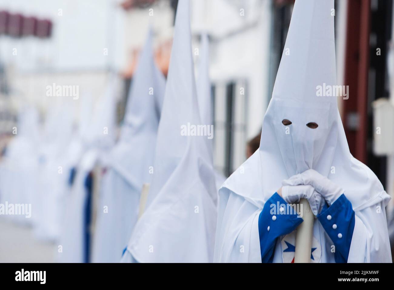 A vertical shot of a person with a white, traditional capirote at the ...