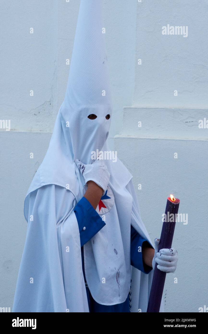 A vertical shot of a person with a white traditional capirote for the ...