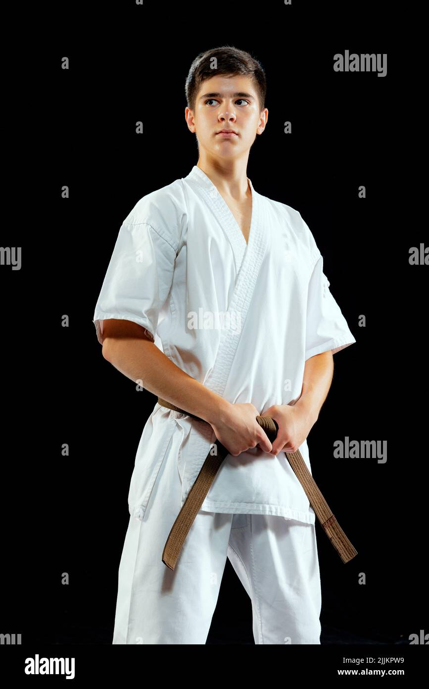 Portrait of young man, karate fighter in white kimono and black belt in ...