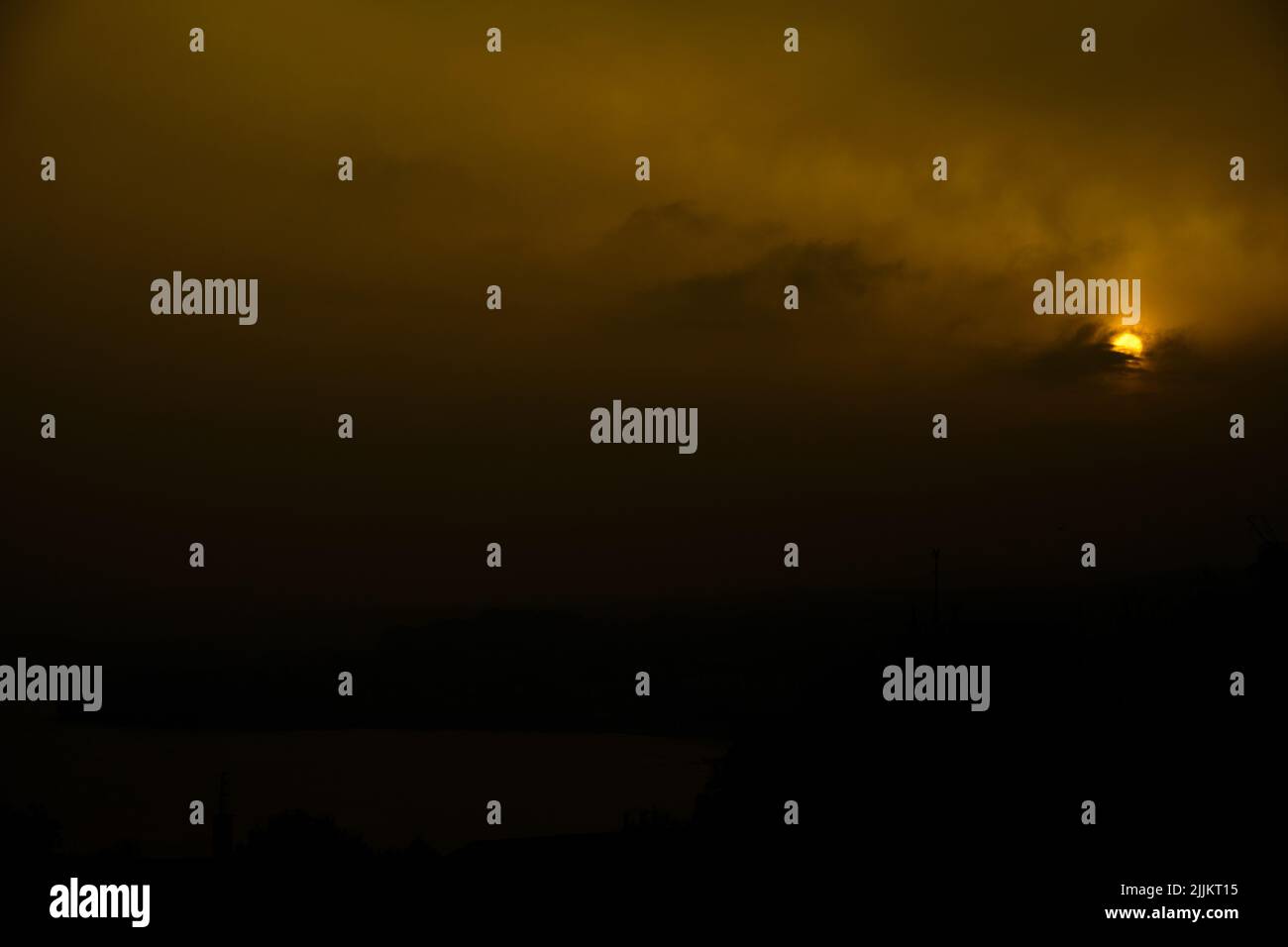 Moody sunset sky and dark clouds with a deep orange sun in stormy ...