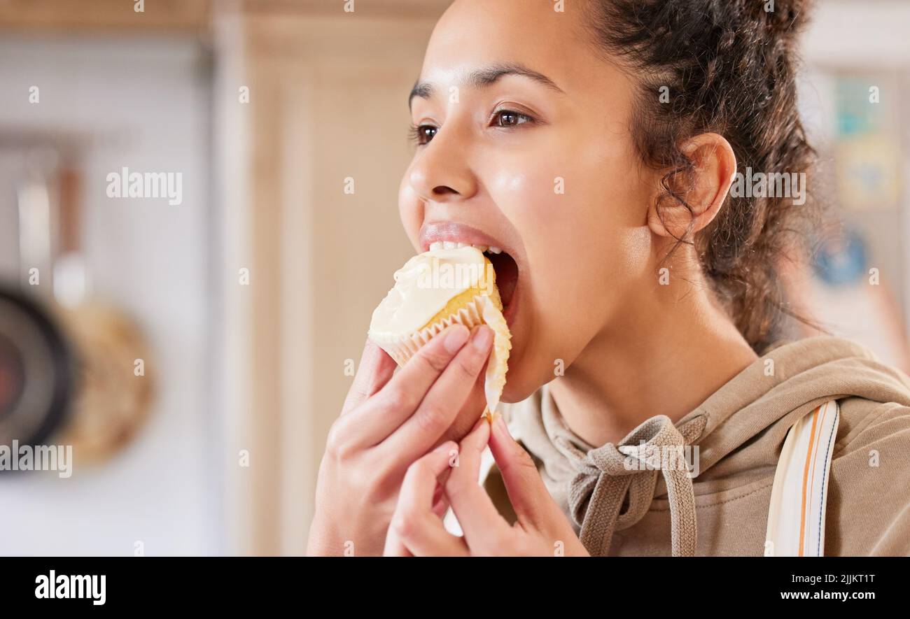 A sweet treat for the chef. a young woman enjoying a baked cupcake ...