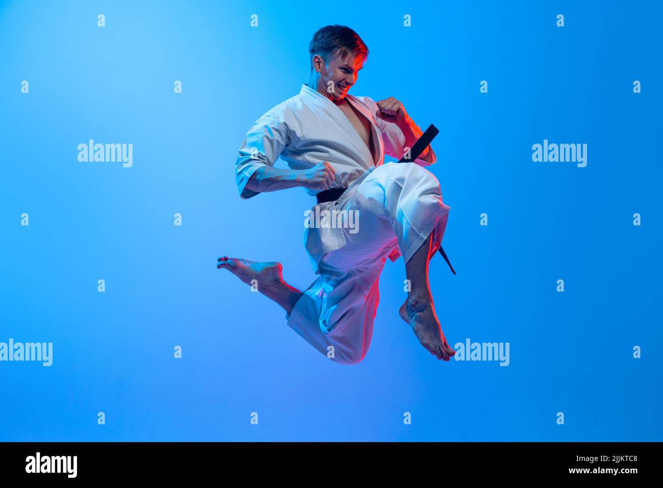 One young man, karate fighter in white kimono in action, motion ...