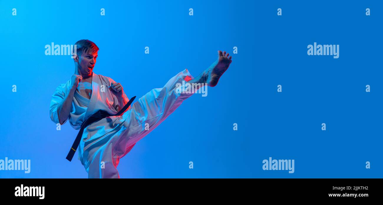 One young man, karate fighter in white kimono in action, motion ...