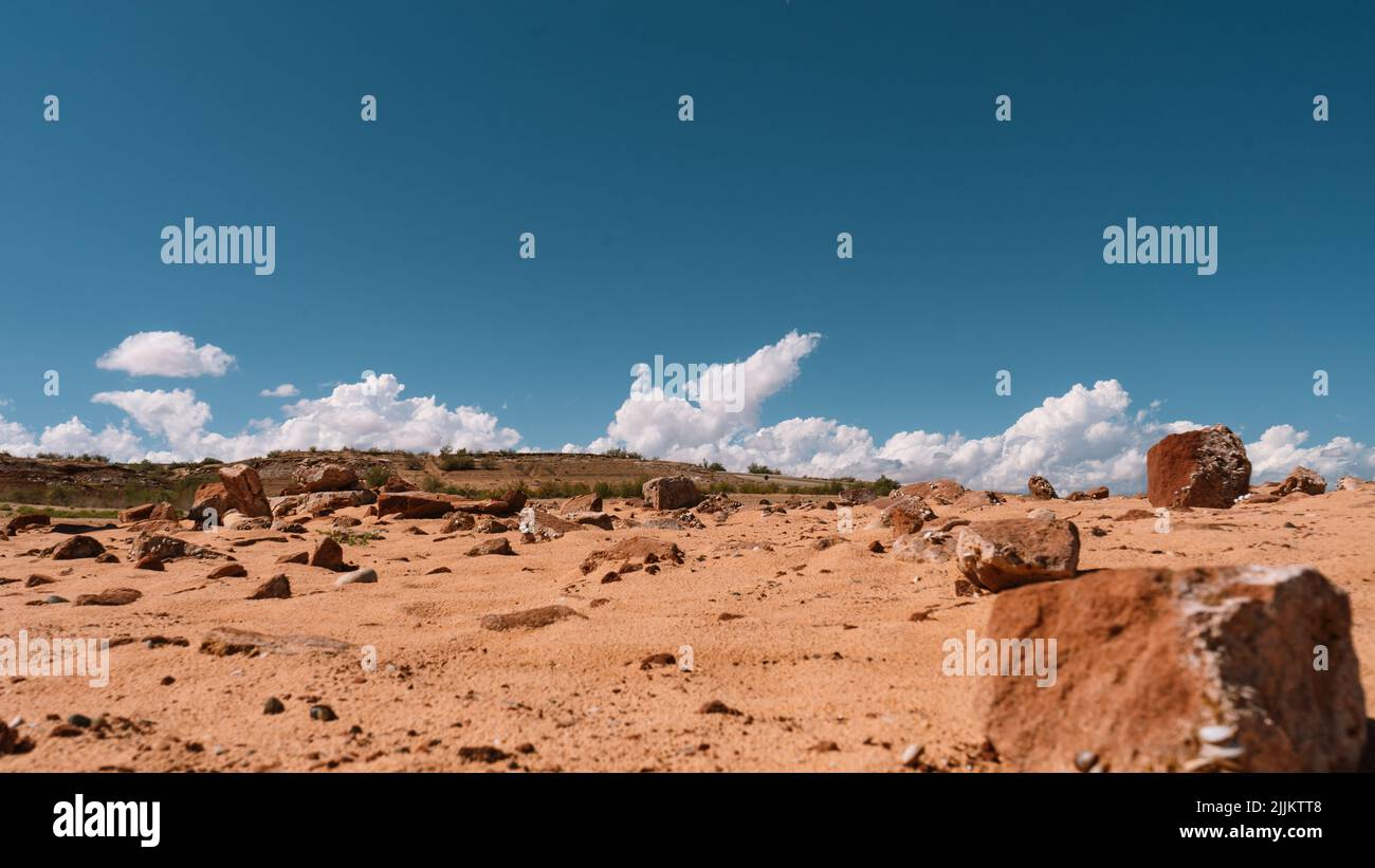 A landscape view of an arid dry desert under a blue cloudy sky on a ...