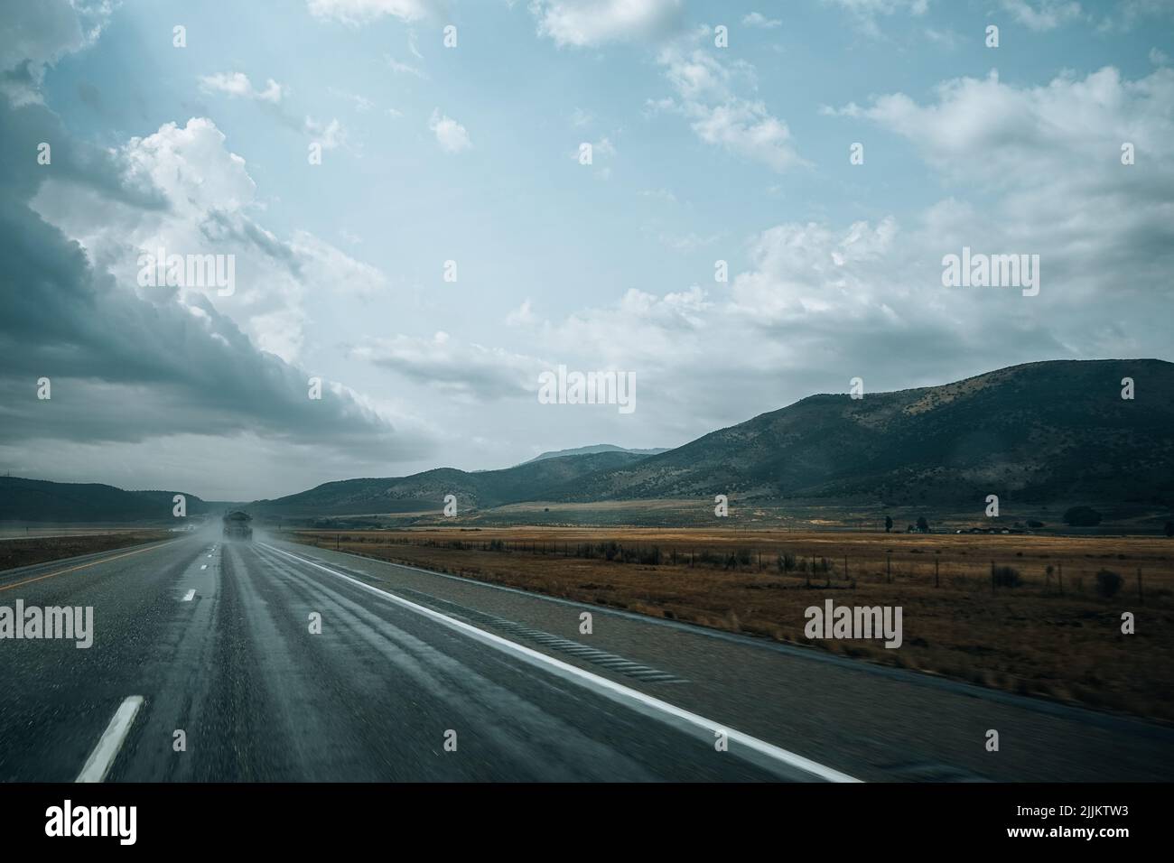 Massive gray clouds over mountains and an empty road on a cold rainy ...