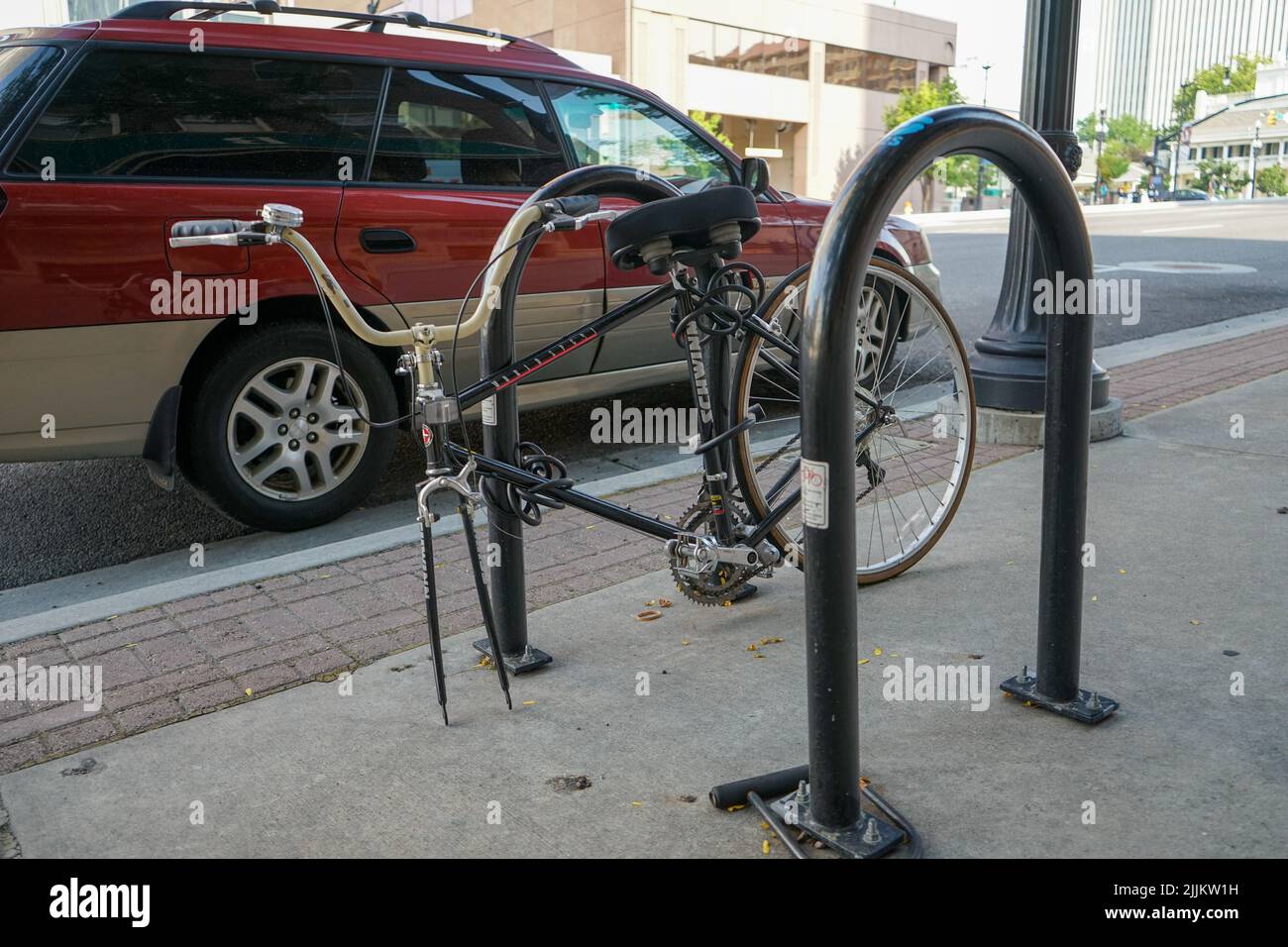 The close-up shot of a broken bike attached to the pole with one ...