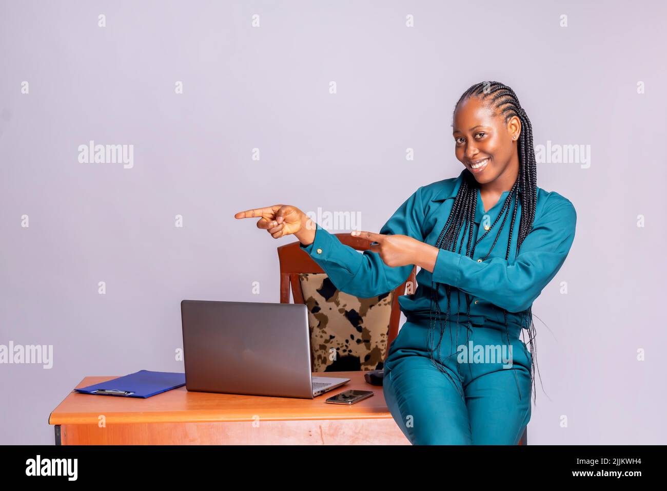 A portrait of a smiling happy African woman pointing to the side ...