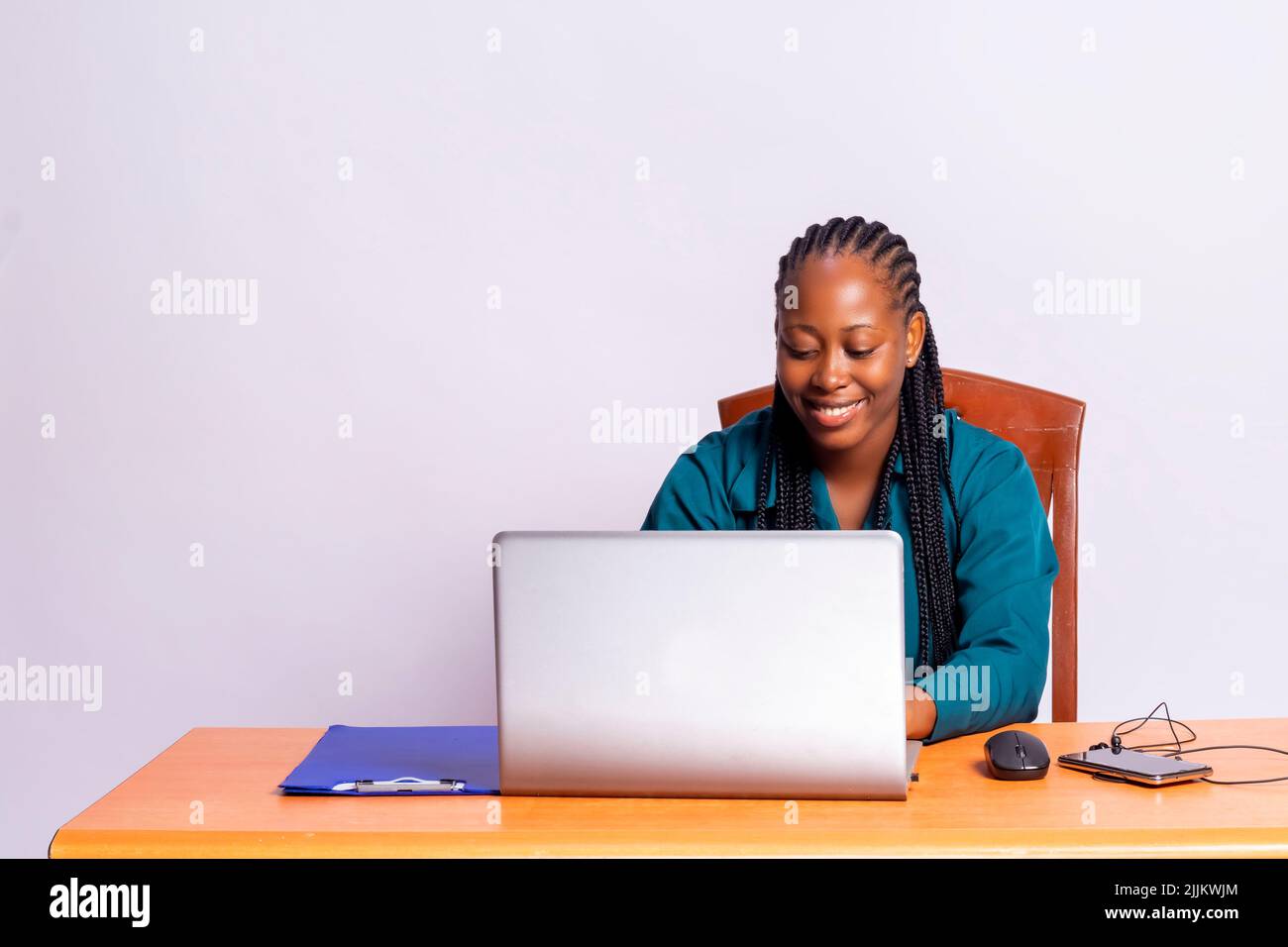 A portrait of an African woman smiling in front of the laptop while ...