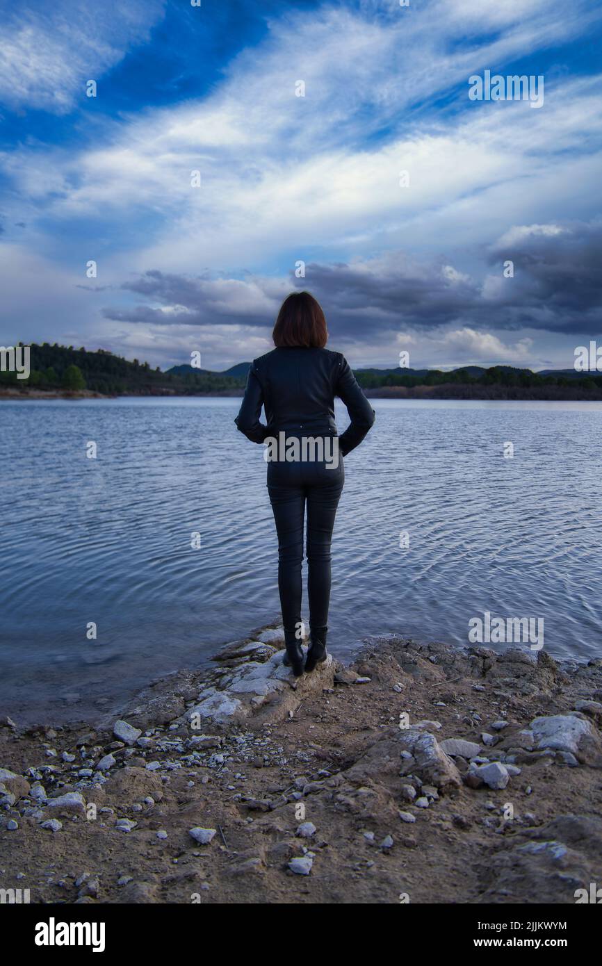 A vertical back view of a female looking at a gloomy lake Stock Photo ...