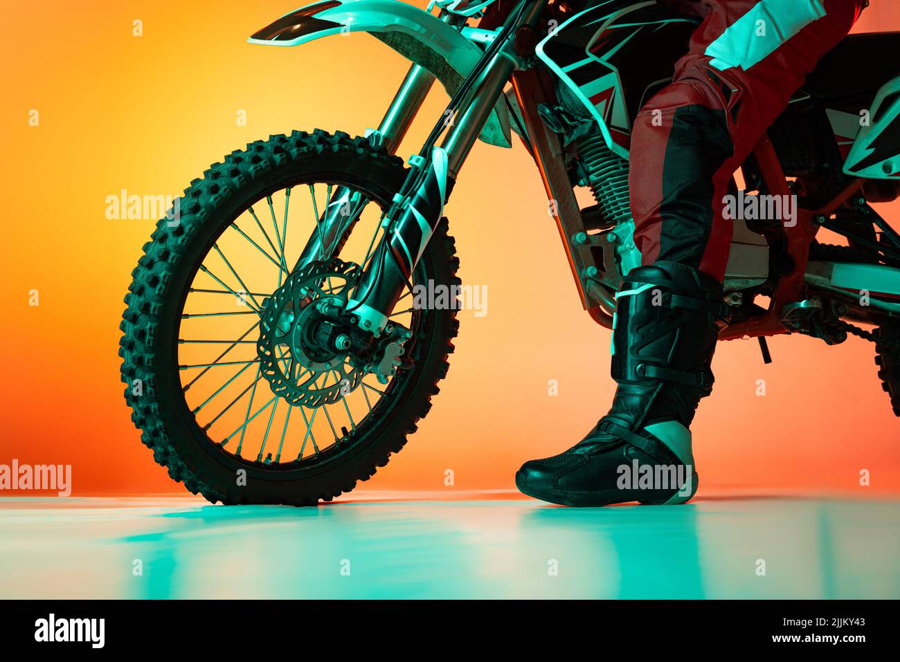 Cropped image of male, biker's leg in boots and tire of motorbike ...