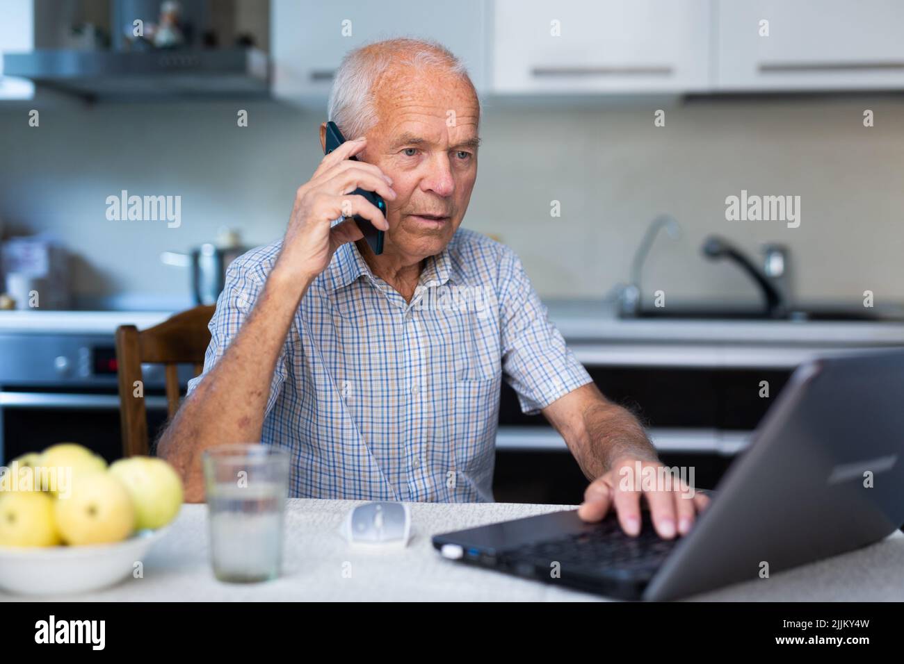 Old man with laptop talking on phone Stock Photo - Alamy
