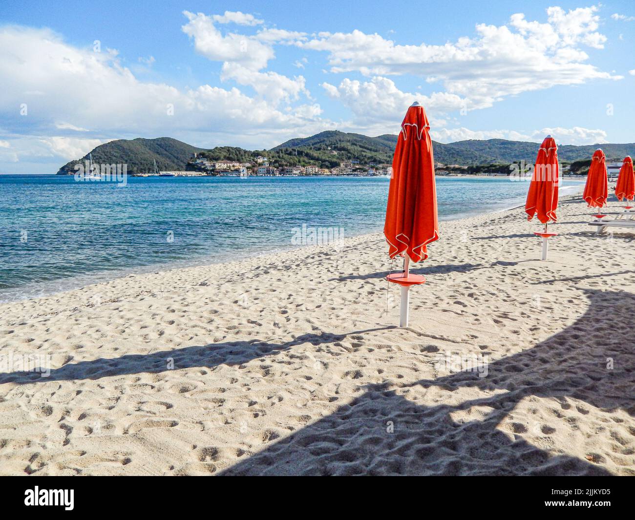 The sunny beaches of Montenegro with red closed umbrellas on the sand ...