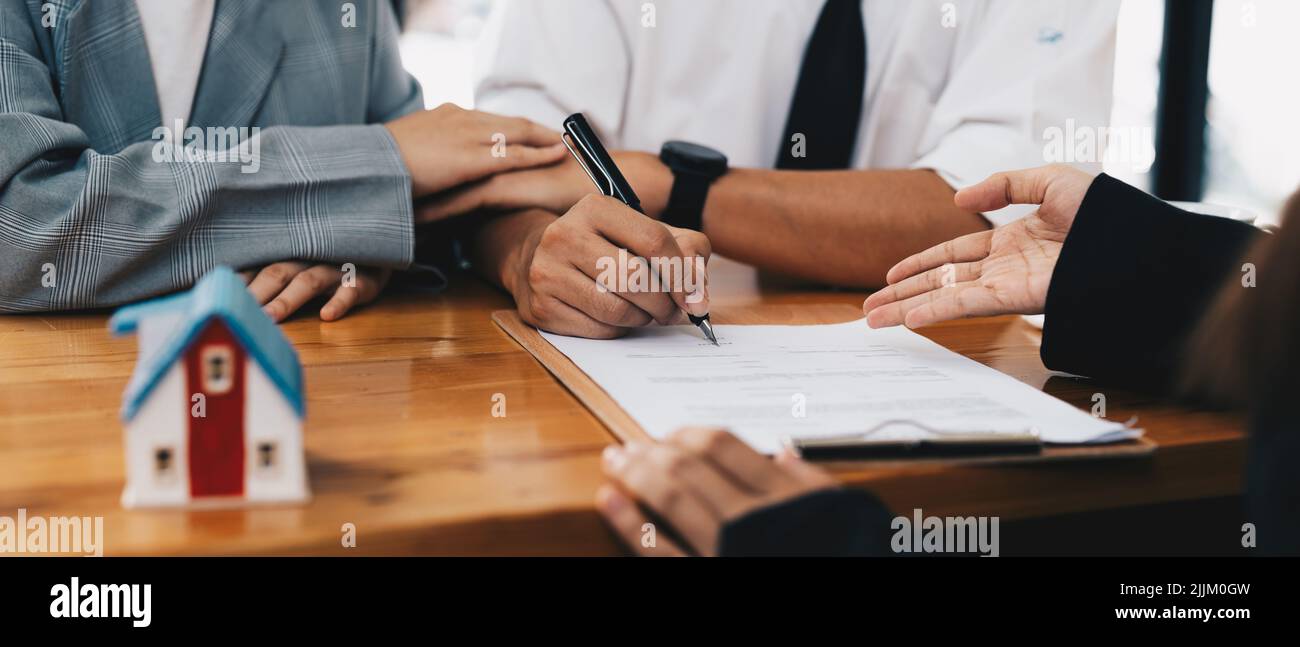 Business woman and young couple signing agreement for buying house ...