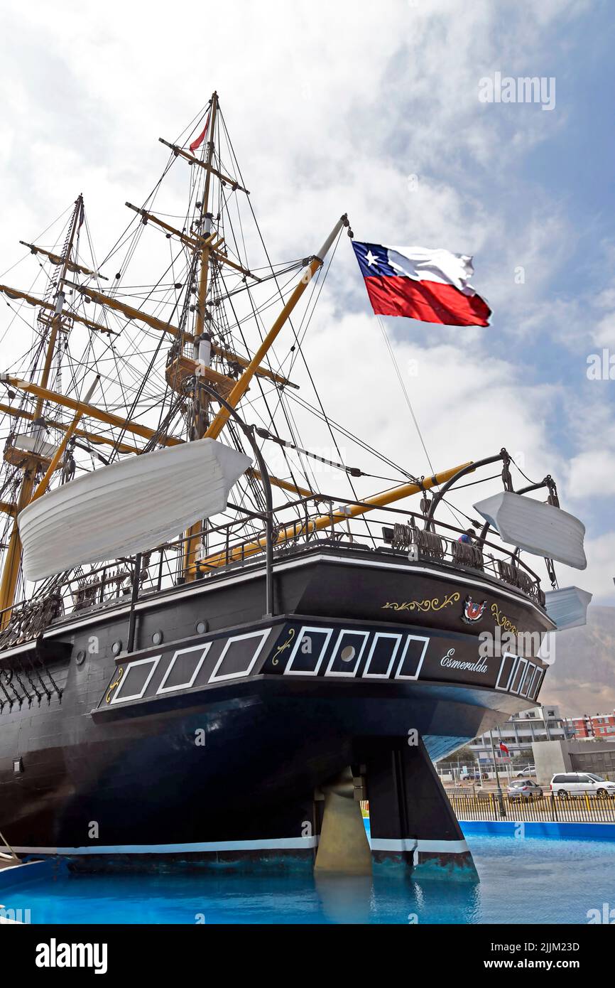 A vertical shot of a huge, black ship with the flag of Chile on it ...