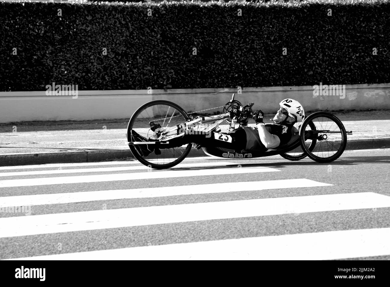 A grayscale shot of a male driving a handicap technology bike at a ...