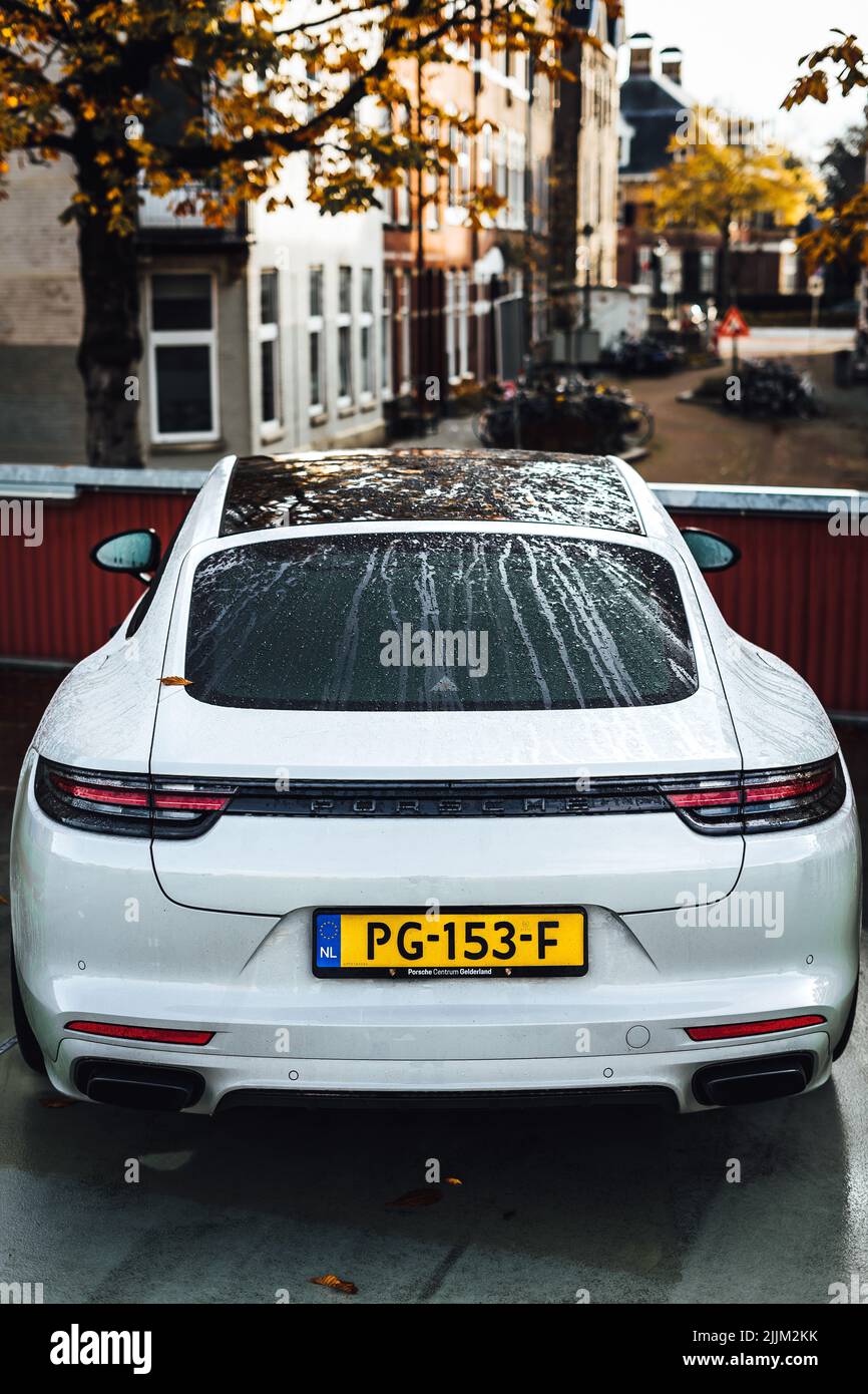 A vertical shot of the back of a white Porsche parked in a street with ...