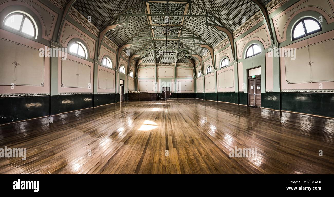 A beautiful shot of a hall with big windows reflecting on the wooden ...