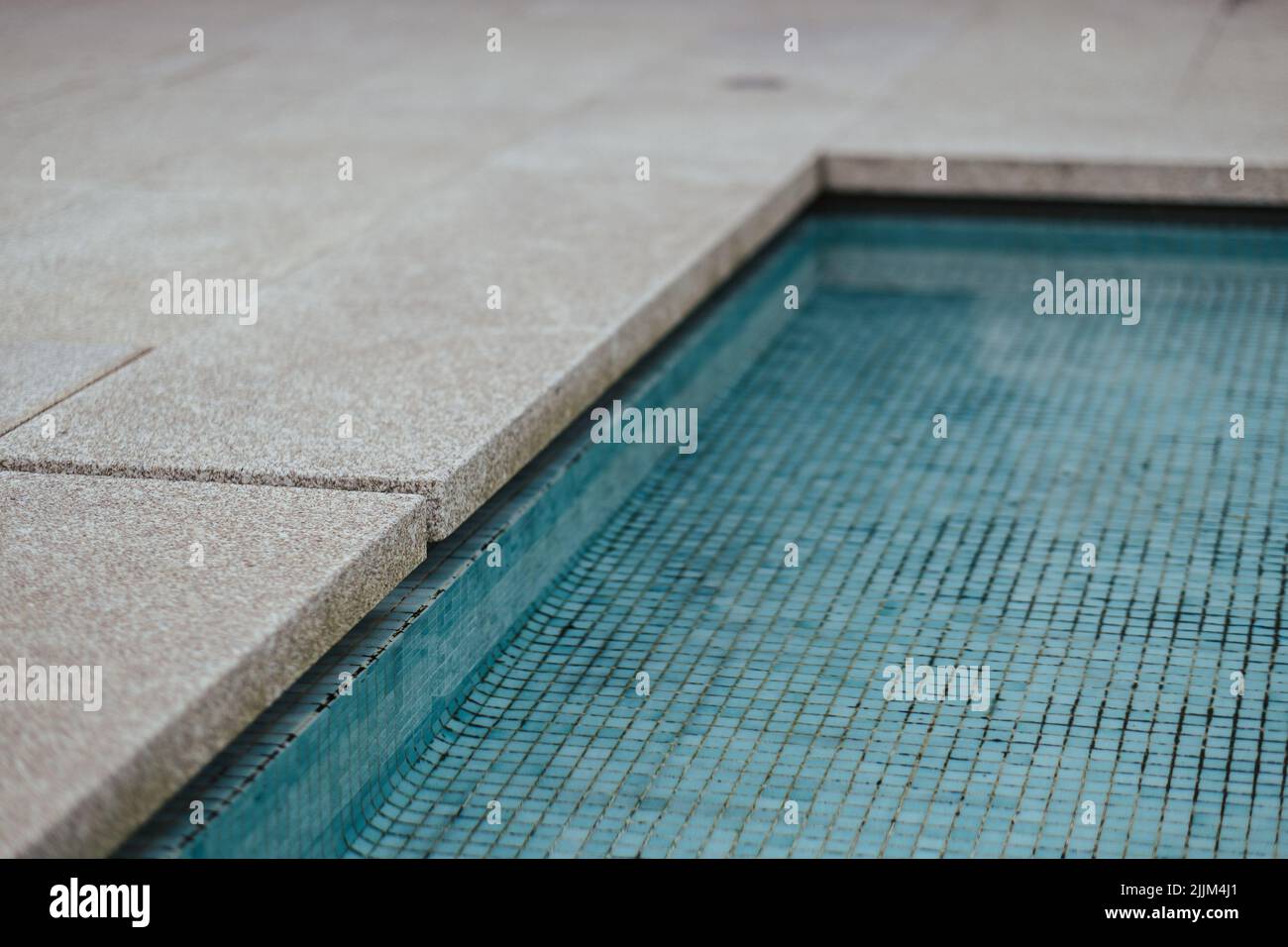 A blue mosaic pool interior near stone sides Stock Photo - Alamy