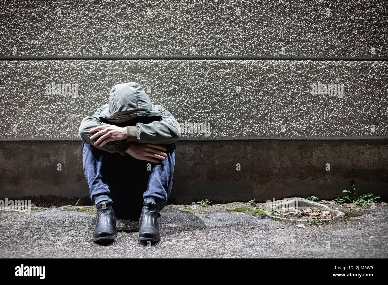 A person in an anorak sitting on the ground with the head and hands on ...