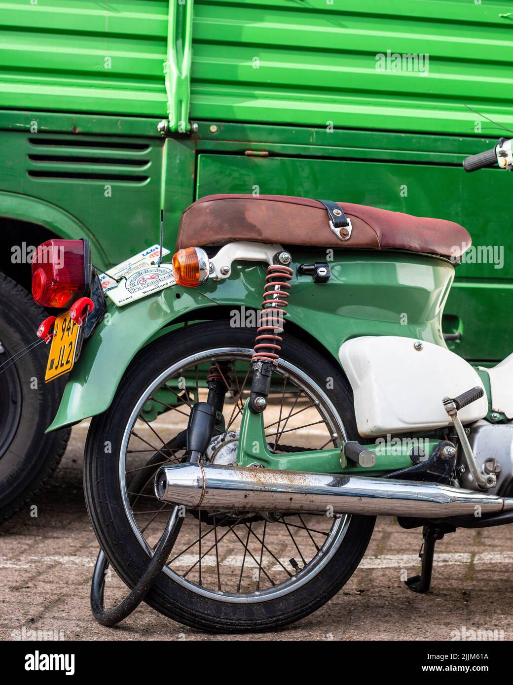 A vertical shot of a green moped in front of green bus Stock Photo - Alamy