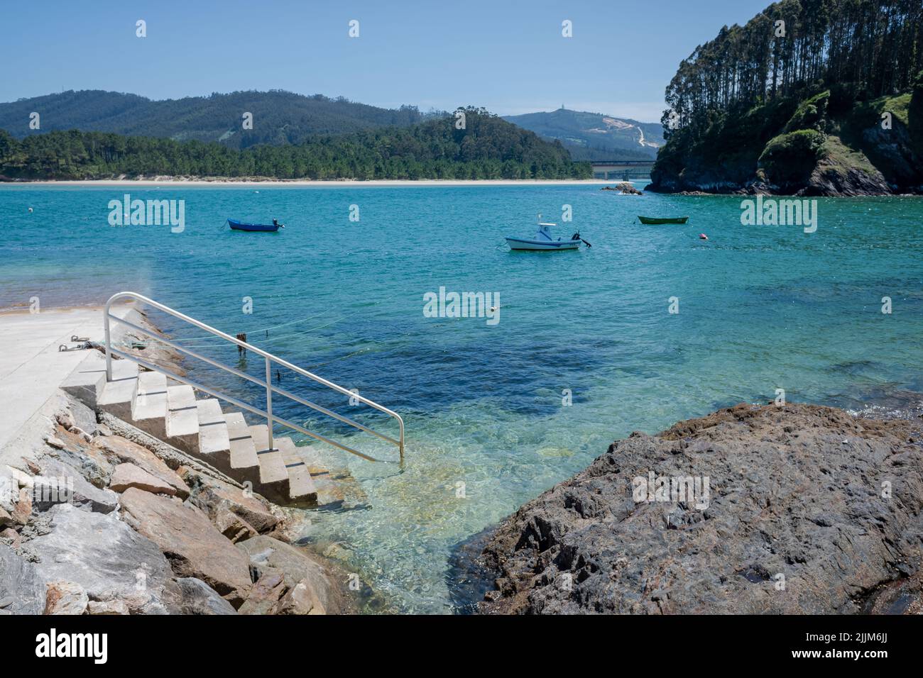 A mesmerizing view of three boats on the sea water in O Barqueiro ...