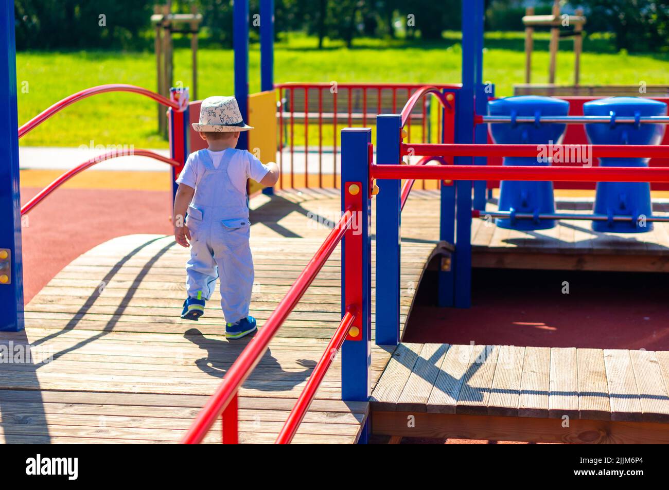 A closeup of a young boy walking on a wooden platform in a playground ...