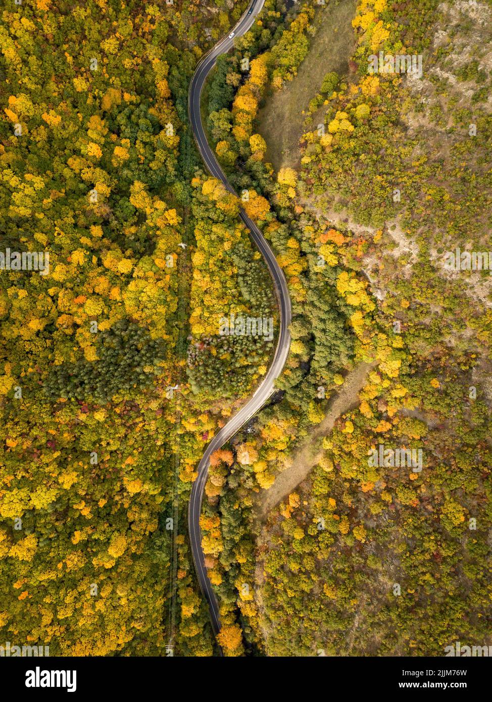An aerial view of a rural trail through mountains with yellow autumn ...