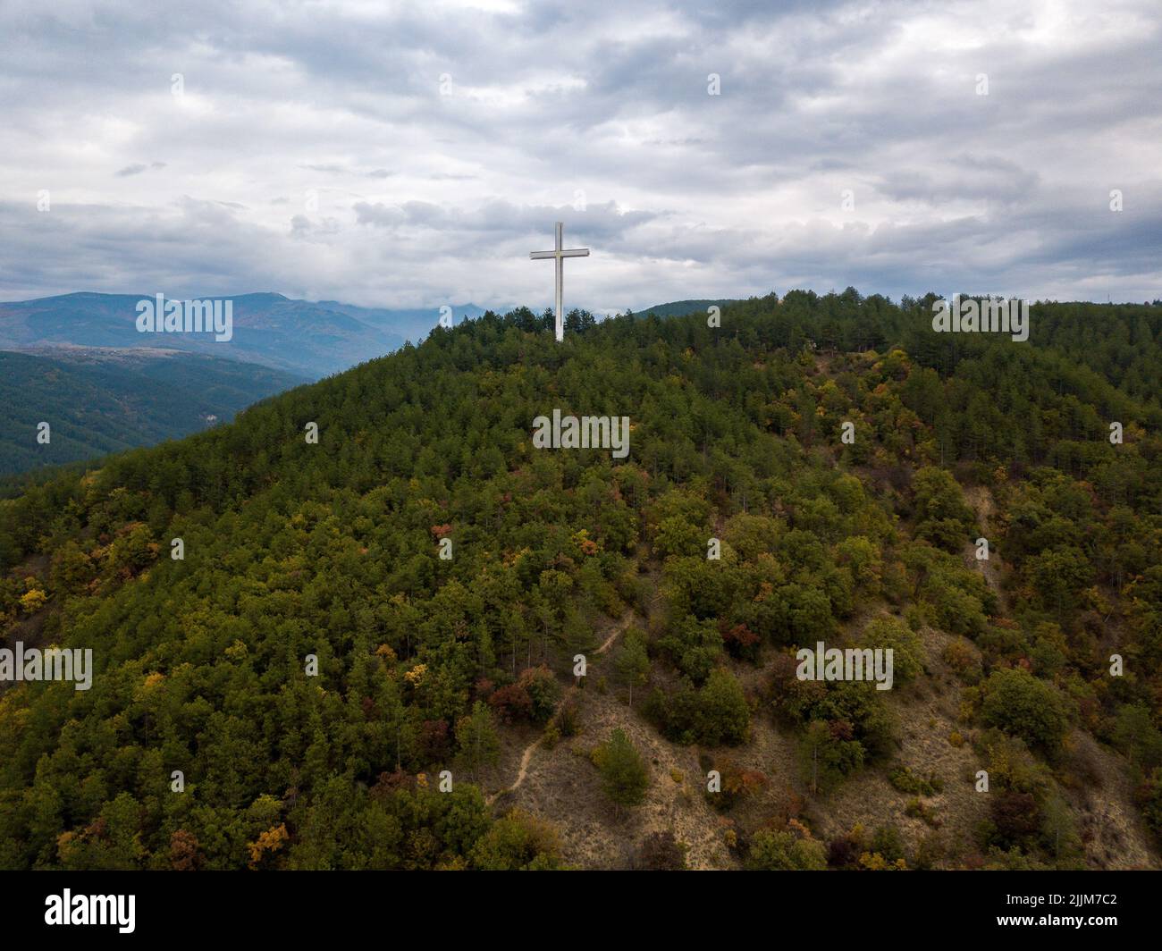 A beautiful view of a green landscape with trees and a cross on a hill ...