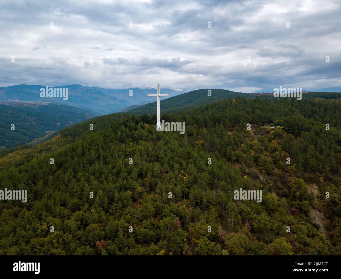 A beautiful view of a green landscape with trees and a cross on a hill ...