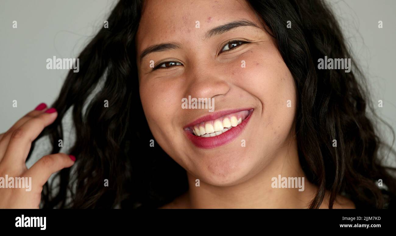 Casual hispanic latina girl looking at camera and touching hair. Close ...