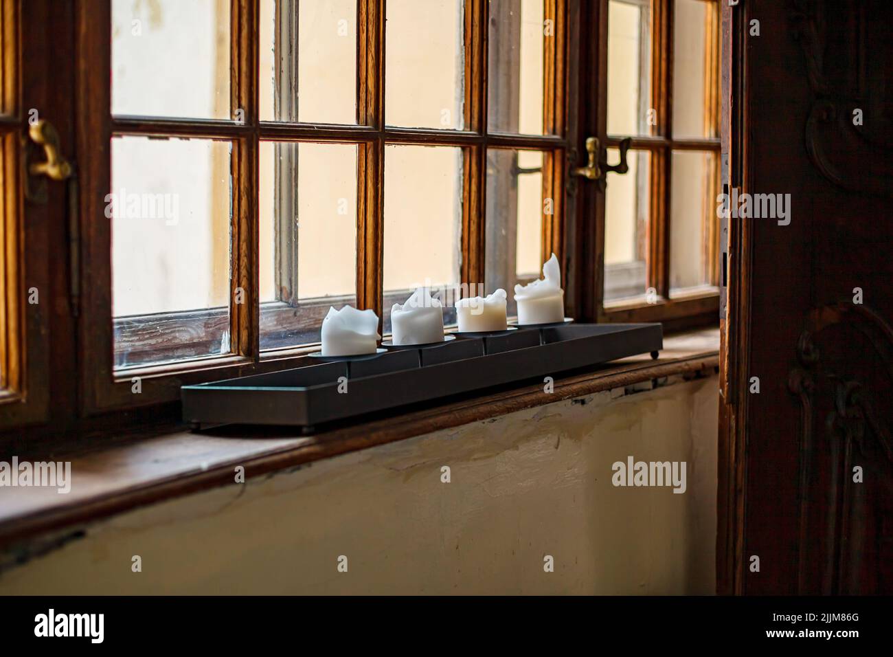 A wooden window sill with a silver container and burnt white candles ...